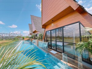 Um edifício moderno com piscina, amplas janelas e vista para a paisagem ao redor.