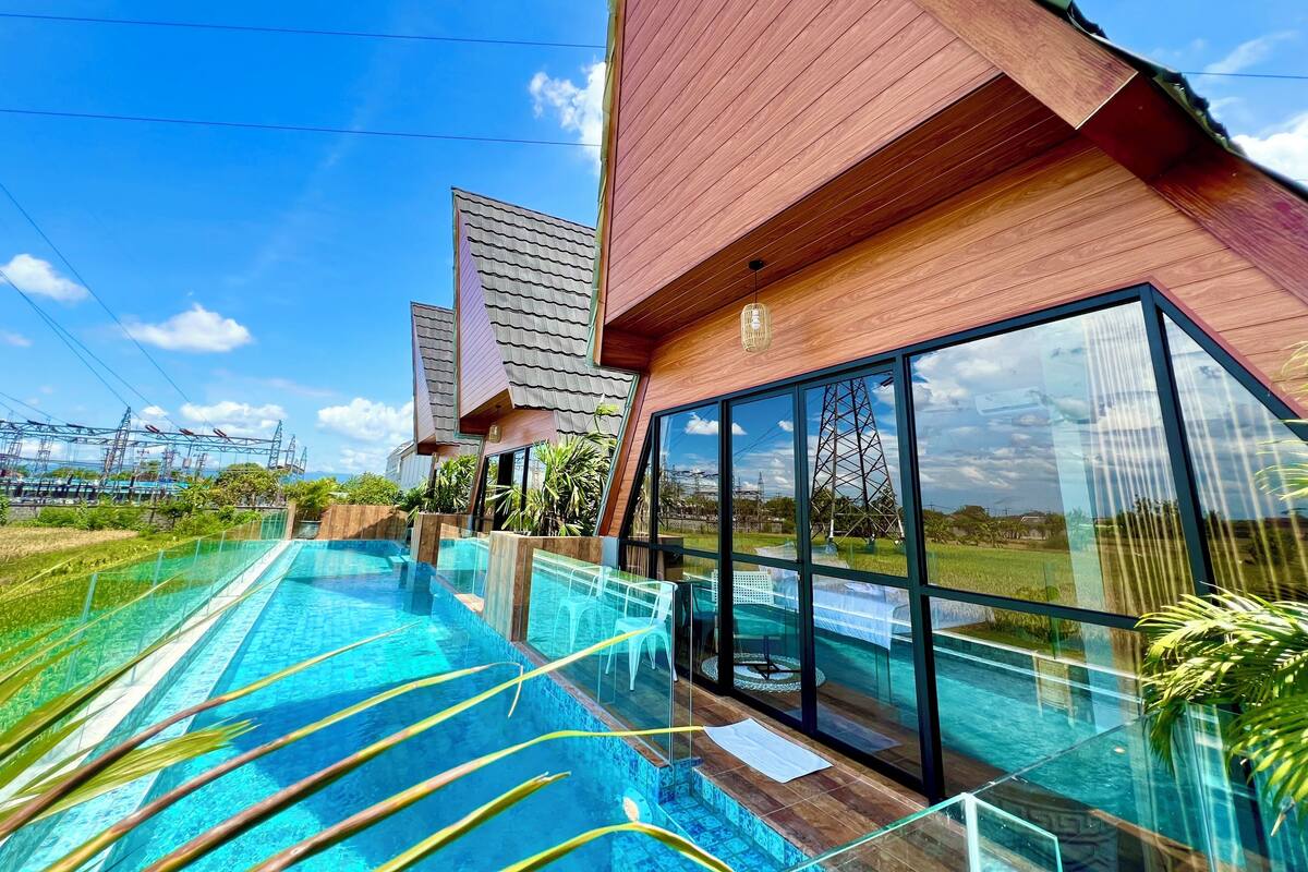 Um edifício moderno com piscina, janelas amplas e vista para a paisagem ao redor.