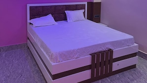 Quarto moderno com cama, cabeceira embutida e teto com iluminação embutida.