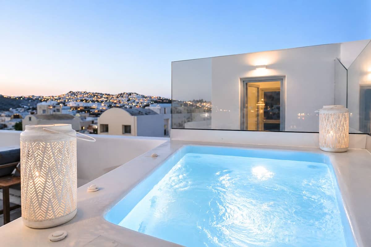 Piscina no terraço com vista para a paisagem urbana ao entardecer.