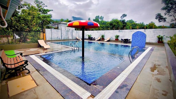 Uma piscina com um guarda-sol colorido, cadeiras de espreguiçadeira e um deck revestido de azulejos.