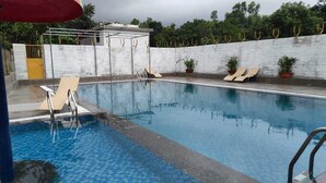 Piscina com espreguiçadeiras e parede de concreto.