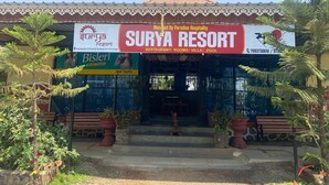 Um edifício com uma placa indicando 'Surya Resort' e um anúncio de 'Bisleri'.