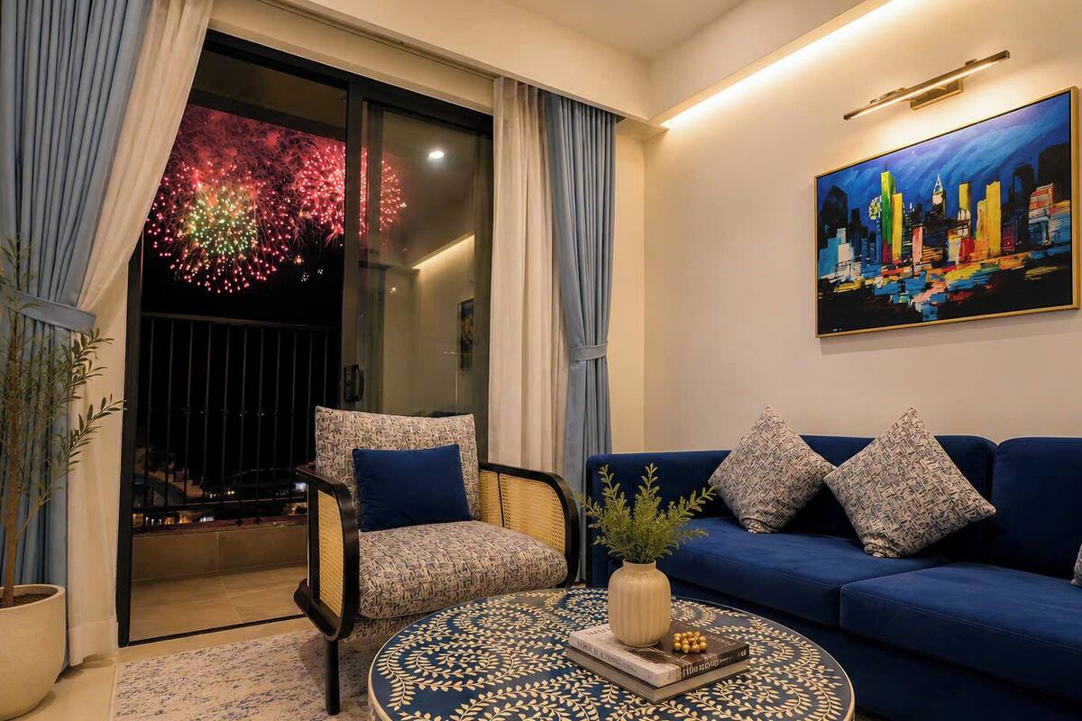 Uma sala de estar moderna com sofá, poltrona, mesa de centro redonda e um quadro na parede.