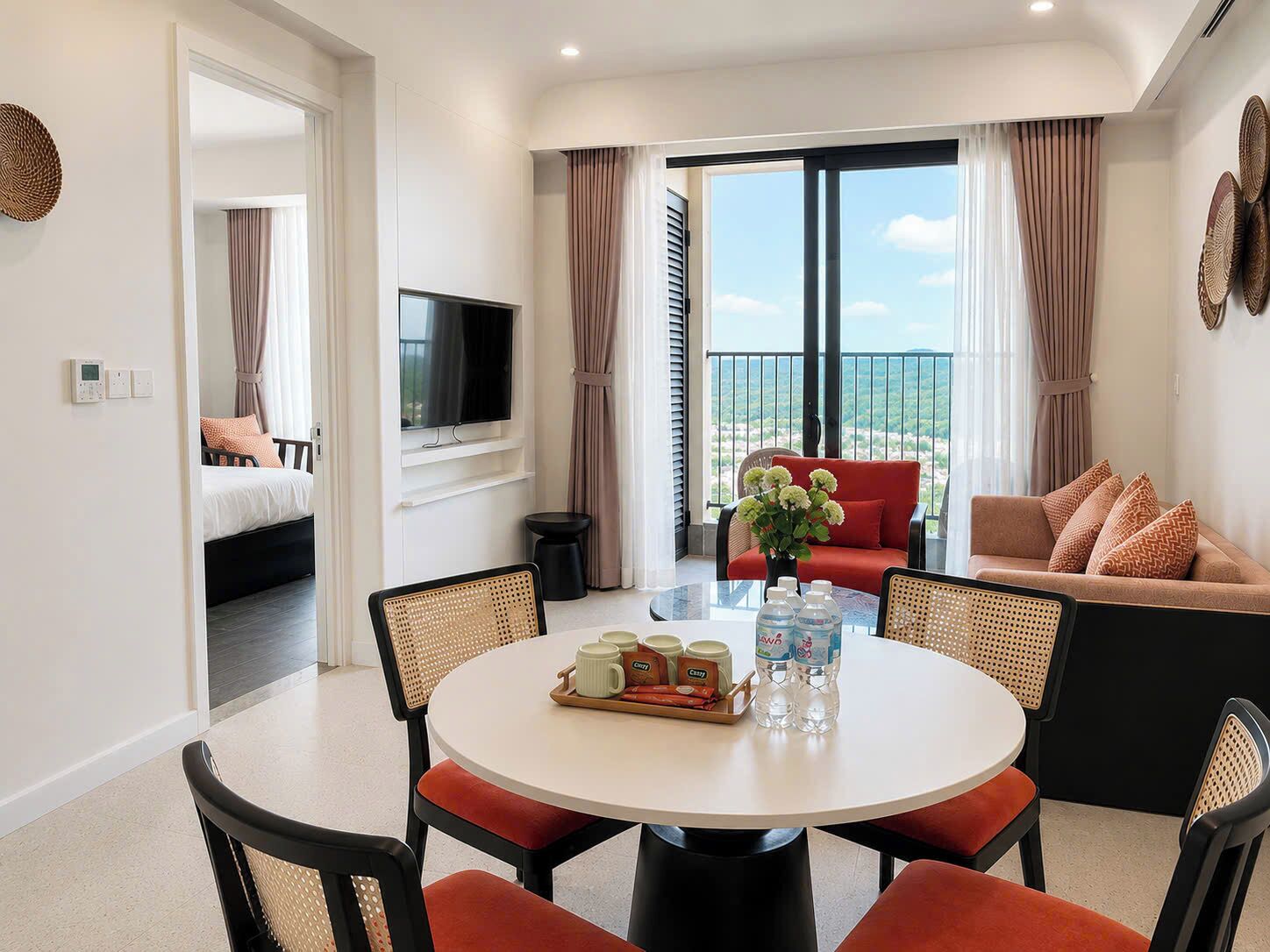 Quarto de hotel moderno com varanda, área de jantar com mesa redonda e um sofá.
