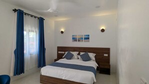 Quarto com cama, cortinas, luzes na parede e um quadro.