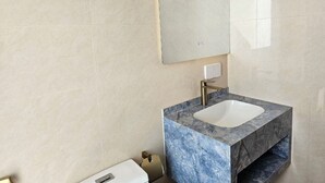 Um banheiro com pia de mármore, porta-toalhas dourado e espelho.