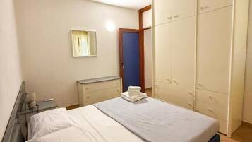 Quarto com cama, penteadeira, guarda-roupa e espelho.