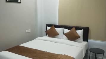Quarto de hotel com cama, uma mesinha e um quadro na parede.