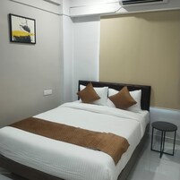 Quarto de hotel com cama, uma mesinha e um quadro na parede.