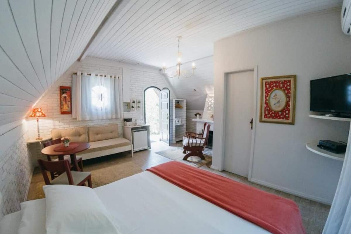 Quarto com cama, sofá, mesa de jantar e televisão.