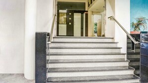 Uma escadaria com corrimão, conduzindo a uma porta com uma placa acima.