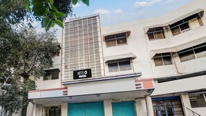 Hotel com letreiro, várias janelas e escadaria que leva à entrada.