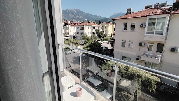 Uma varanda com vista para uma área residencial, incluindo edifícios e uma montanha ao fundo.