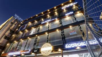 Um hotel com vários andares, com sinalização iluminada para 'Amigo Premium Stay' e 'Mithai Mahal'.