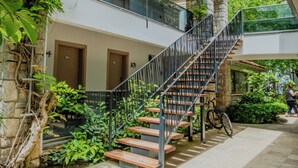 Um edifício com vários níveis, uma escadaria, paredes de pedra e vegetação.