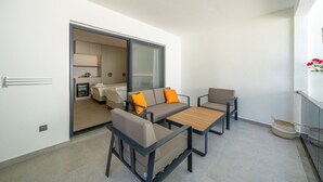 Uma varanda com sofá, cadeiras e uma mesa.