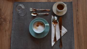 Uma mesa com uma chávena de café, um copo e talheres sobre um guardanapo.