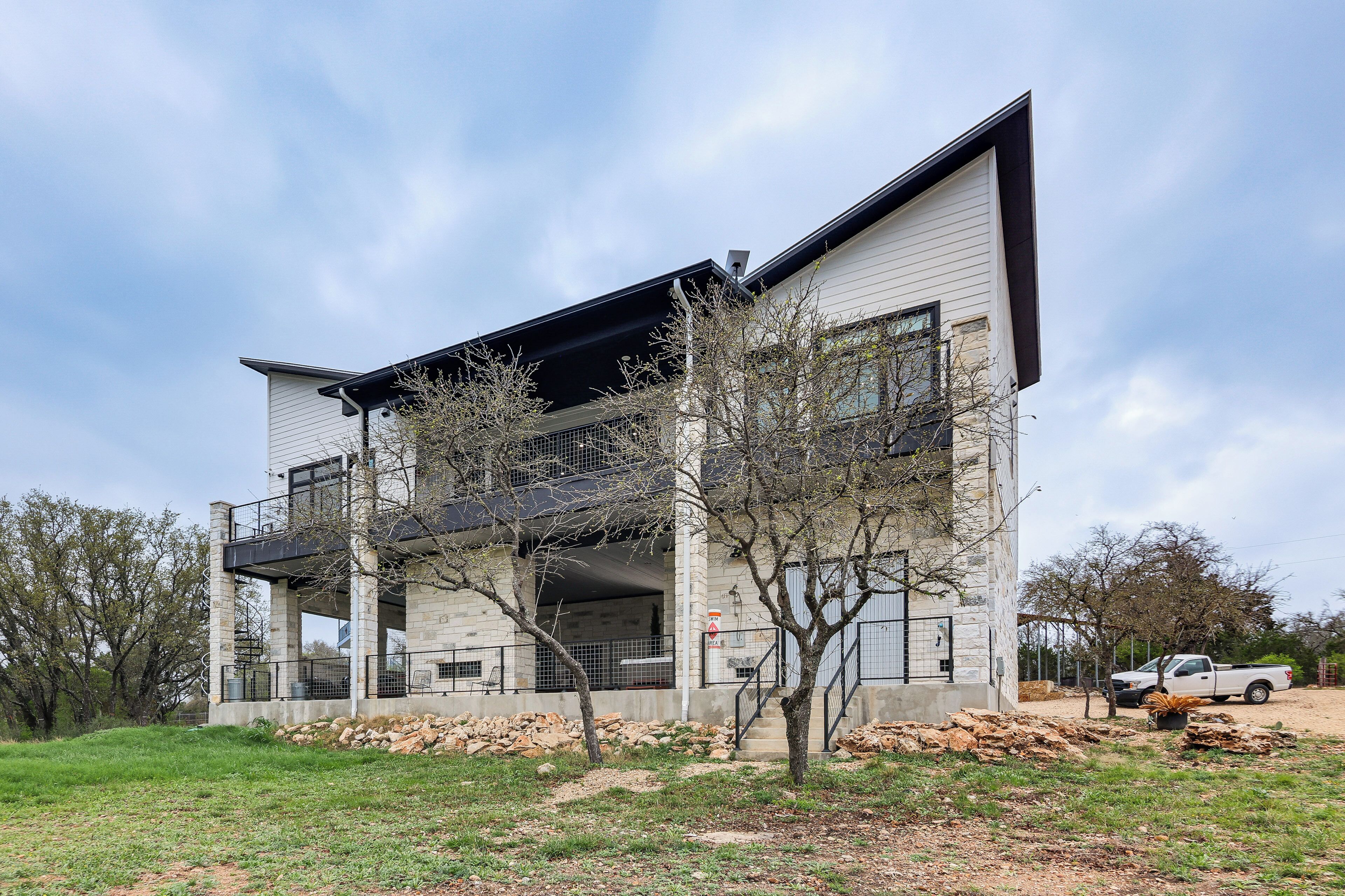 Uma casa moderna de dois andares, com varanda, entrada para carros e uma caminhonete estacionada.