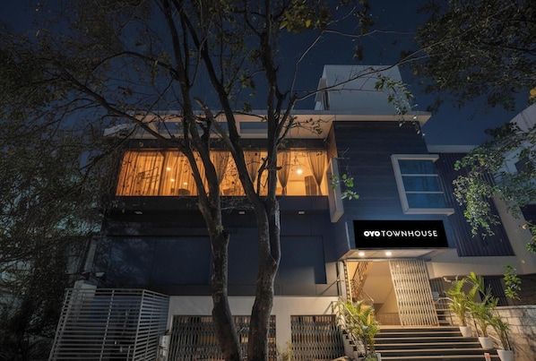 Um edifício moderno de dois andares com entrada visível e uma placa com a inscrição 'OYO TOWNHOUSE'.