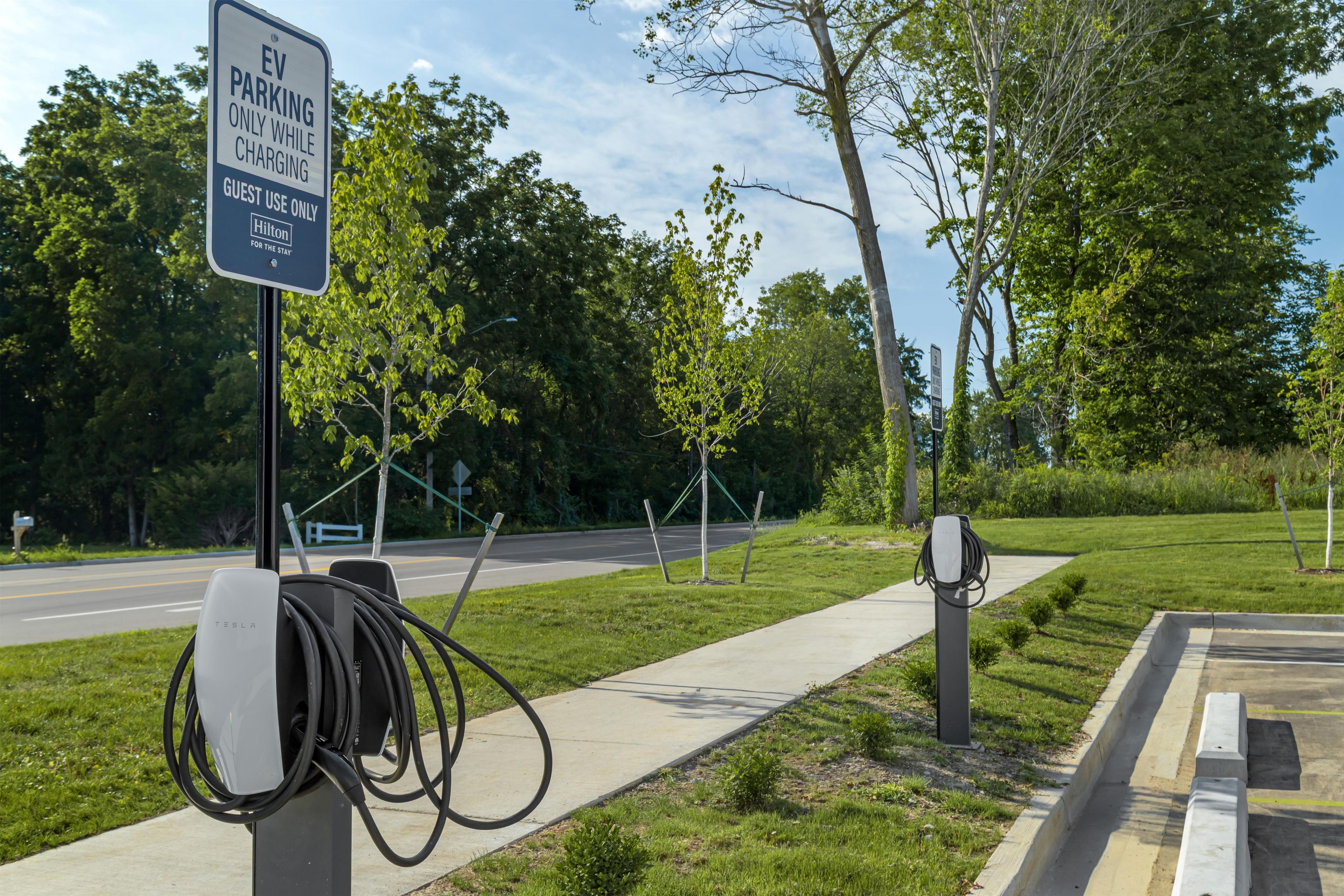 Estação de carregamento para veículos elétricos, com placa indicando uso exclusivo para hóspedes Hilton.
