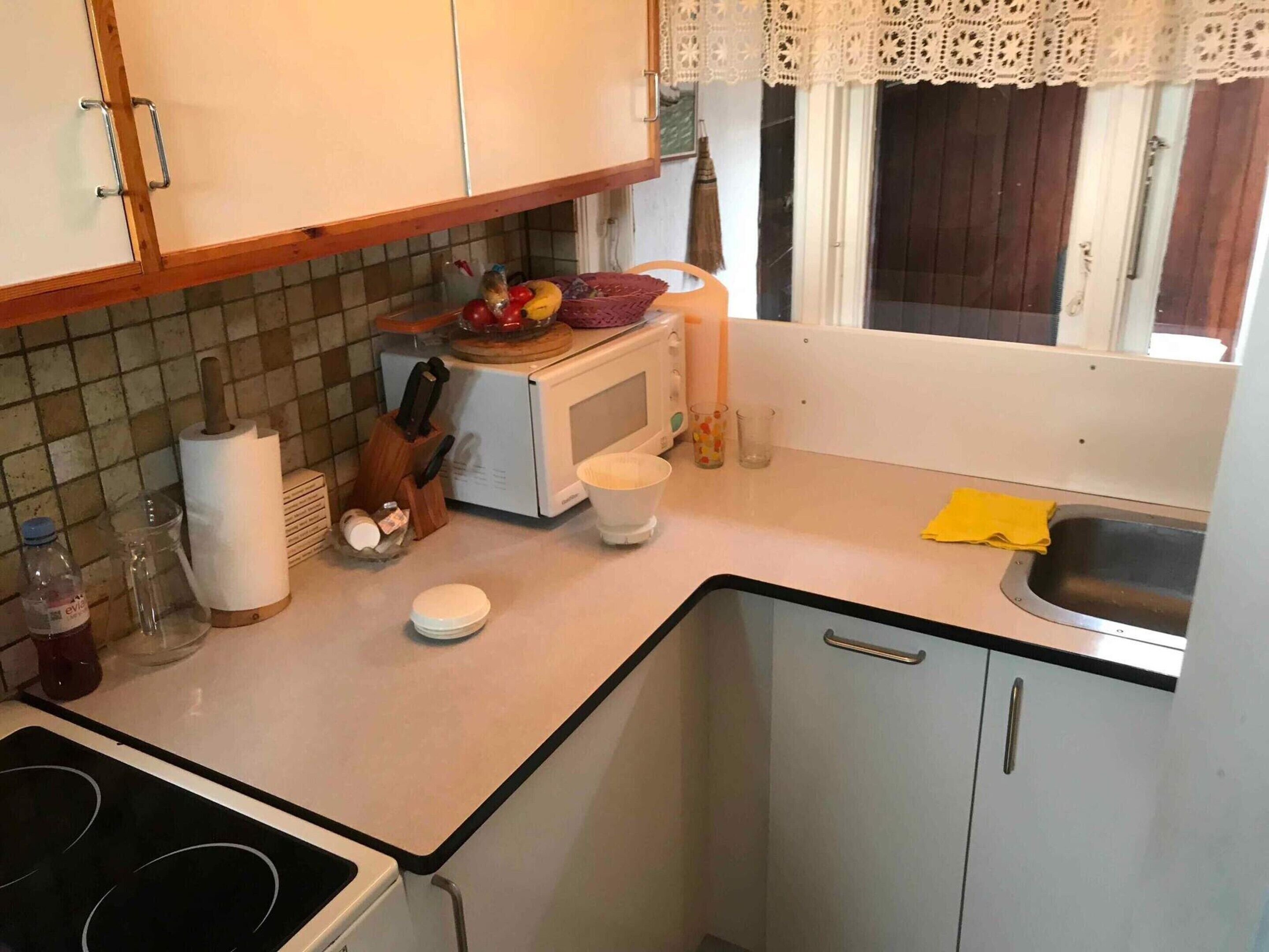 Cozinha compacta com micro-ondas, fogão e pia.