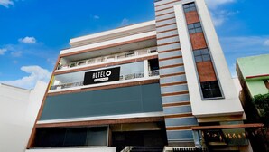 Hotel com design moderno, destacando uma placa visível, vários andares e uma escadaria que leva à entrada.