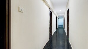 Um corredor comprido e estreito, com paredes brancas e chão preto.