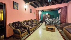 Quarto com sofá, uma mesa pequena e uma cadeira de vime.
