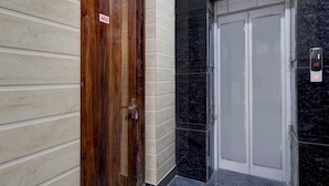 Uma porta de madeira com um símbolo de número, uma porta branca com teclado numérico, e uma parede revestida de azulejos pretos.