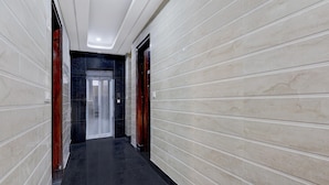 Um corredor com paredes azulejadas, chão preto e uma porta no final.