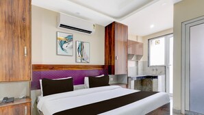 Quarto de hotel com cama, escrivaninha, armário e banheiro visível por uma porta aberta.
