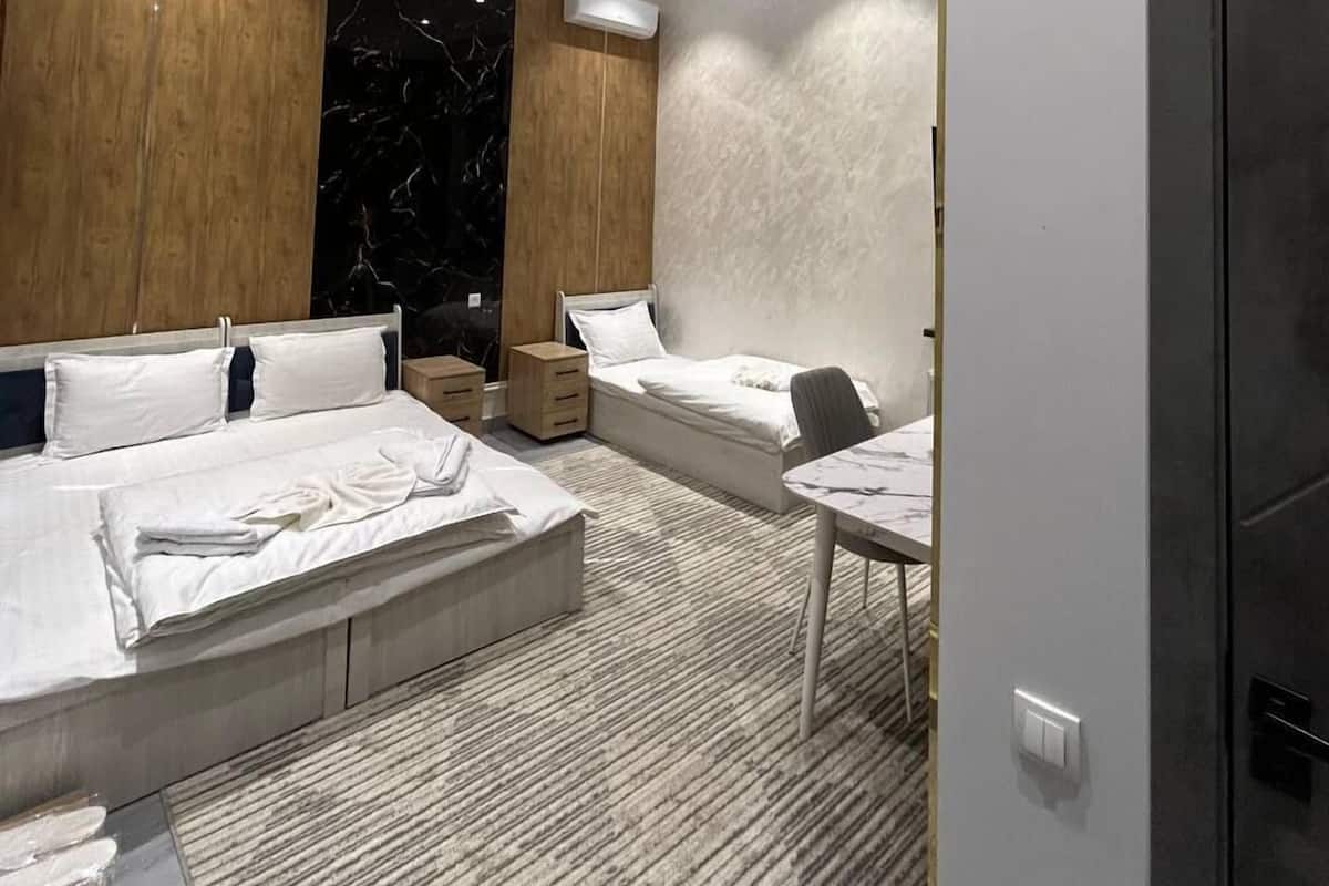 Quarto moderno com duas camas, uma escrivaninha e um guarda-roupa.
