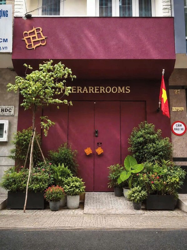 Um edifício com fachada cor de vinho, um letreiro com a inscrição 'ERAREROOMS' e uma bandeira.