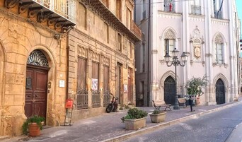 Rua com edifícios históricos, uma loja fechada e uma bicicleta estacionada.