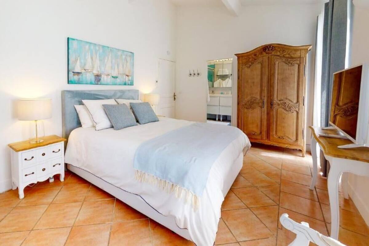 Quarto com cama, mesa de cabeceira, cômoda, guarda-roupa e um quadro na parede.