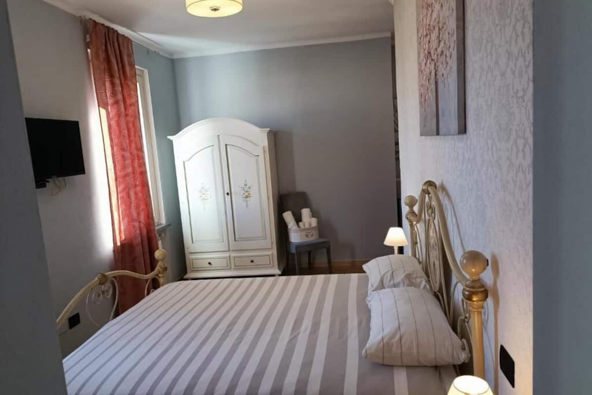 Quarto com cama, guarda-roupa, televisão e abajur.