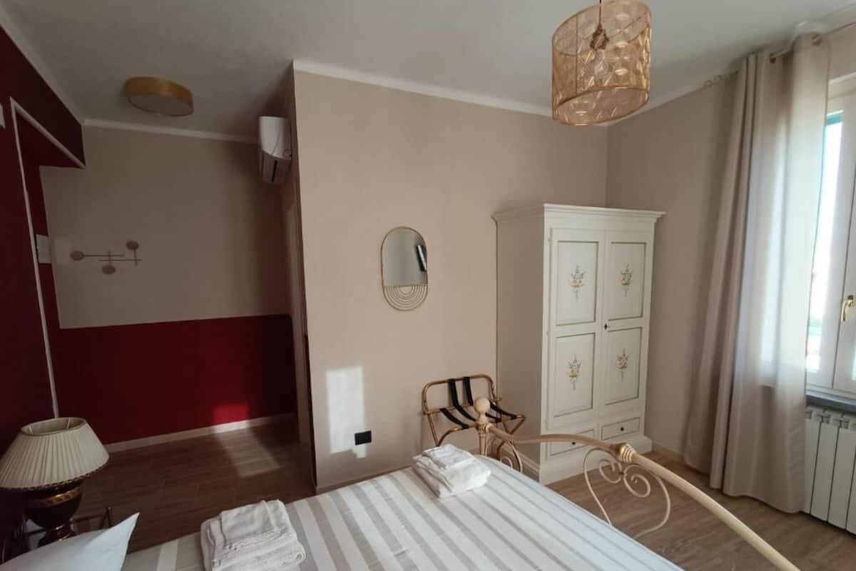 Quarto de hotel com cama, guarda-roupa, cadeira, luminária e espelho.