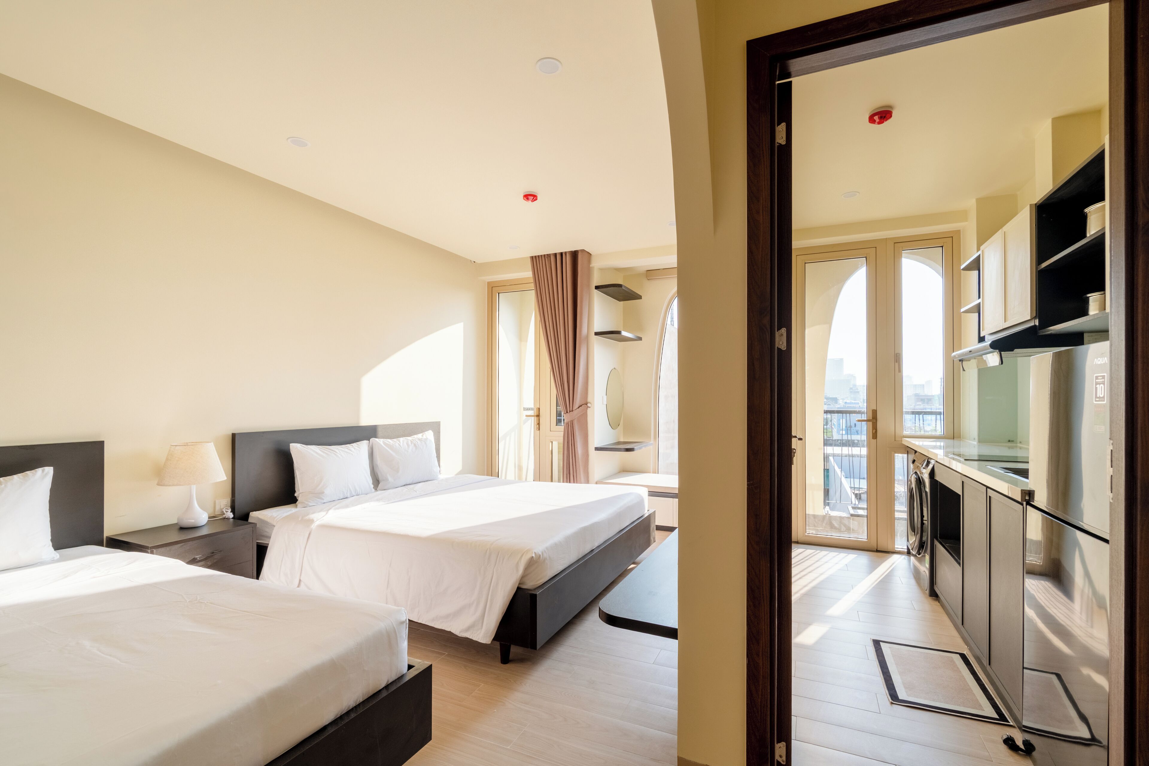 Quarto de hotel com duas camas, uma cozinha compacta e vista para a cidade.