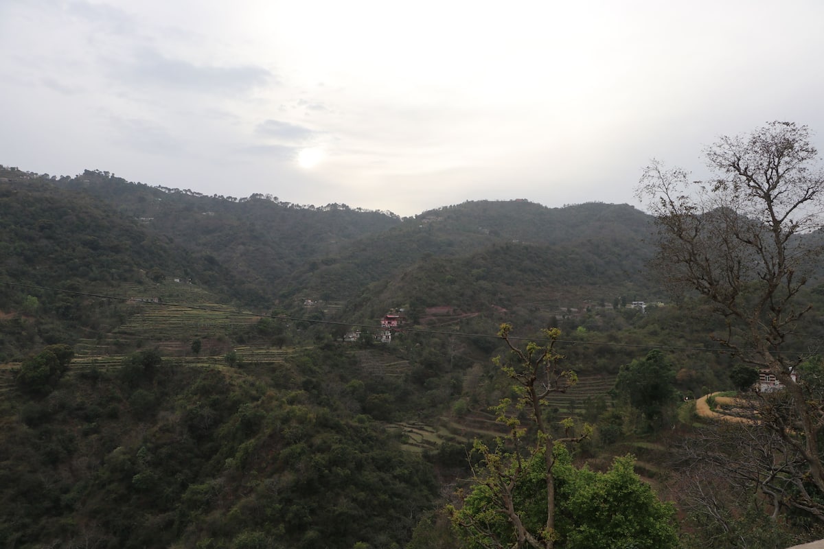 Paisagem acidentada com campos em socalcos e alguns edifícios dispersos.