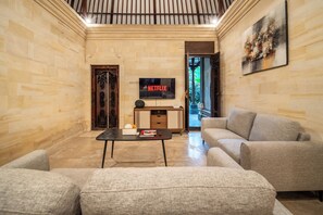 Uma sala de estar moderna com televisão de tela plana, sofá, mesa de centro e porta que dá para uma varanda.