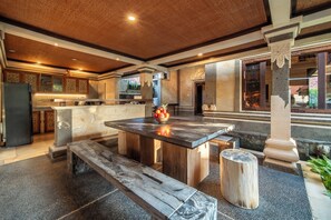 Cozinha espaçosa com uma ilha grande, piso de madeira e bancada de pedra.