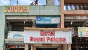 Um edifício com uma placa indicando 'Hotel Royal Palace', com informação sobre quartos com ar condicionado e sem ar condicionado.