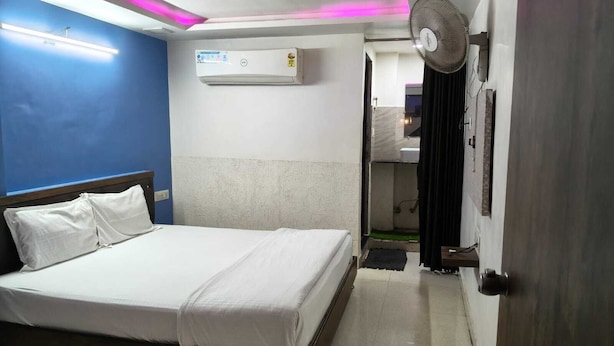 Quarto de hotel com cama, ar condicionado, ventoinha no teto e porta para o banheiro.
