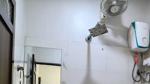 Casa de banho com lavatório, espelho, chuveiro e porta-toalhas.