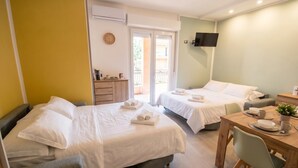 Quarto de hotel com duas camas, uma mesa de jantar, uma TV e uma varanda.