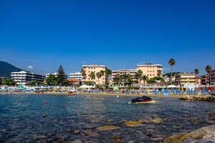 Uma área costeira com praia, edifícios e um barco.