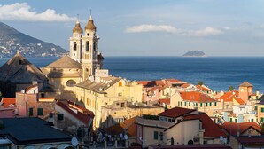 Uma vila costeira com uma igreja imponente, edifícios coloridos e vista para o mar.