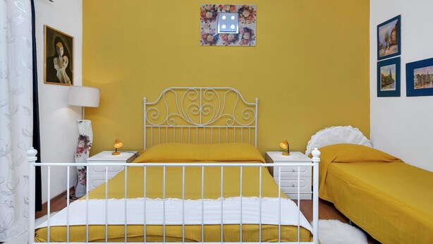 Quarto com cama, mesas de cabeceira, luminária e interruptor de luz na parede.