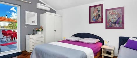 Quarto com cama, penteadeira, cadeira e obra de arte na parede.
